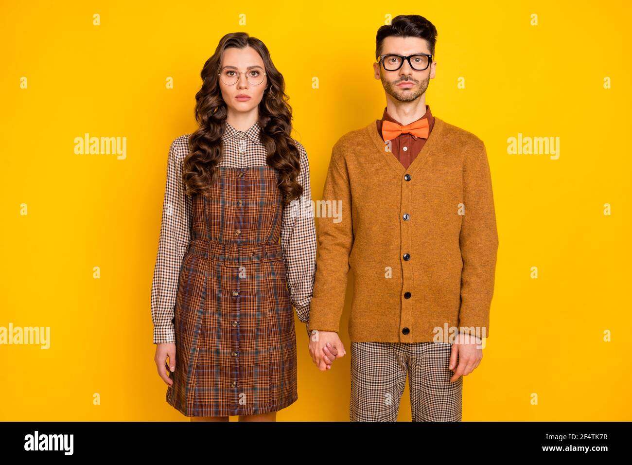 Portrait of attractive serious couple wearing checked uniform holding ...