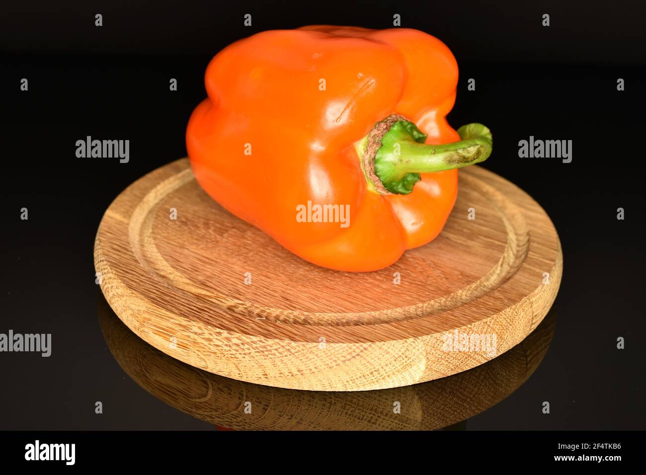 One whole, organic ripe juicy bell pepper, on a round bamboo tray ...