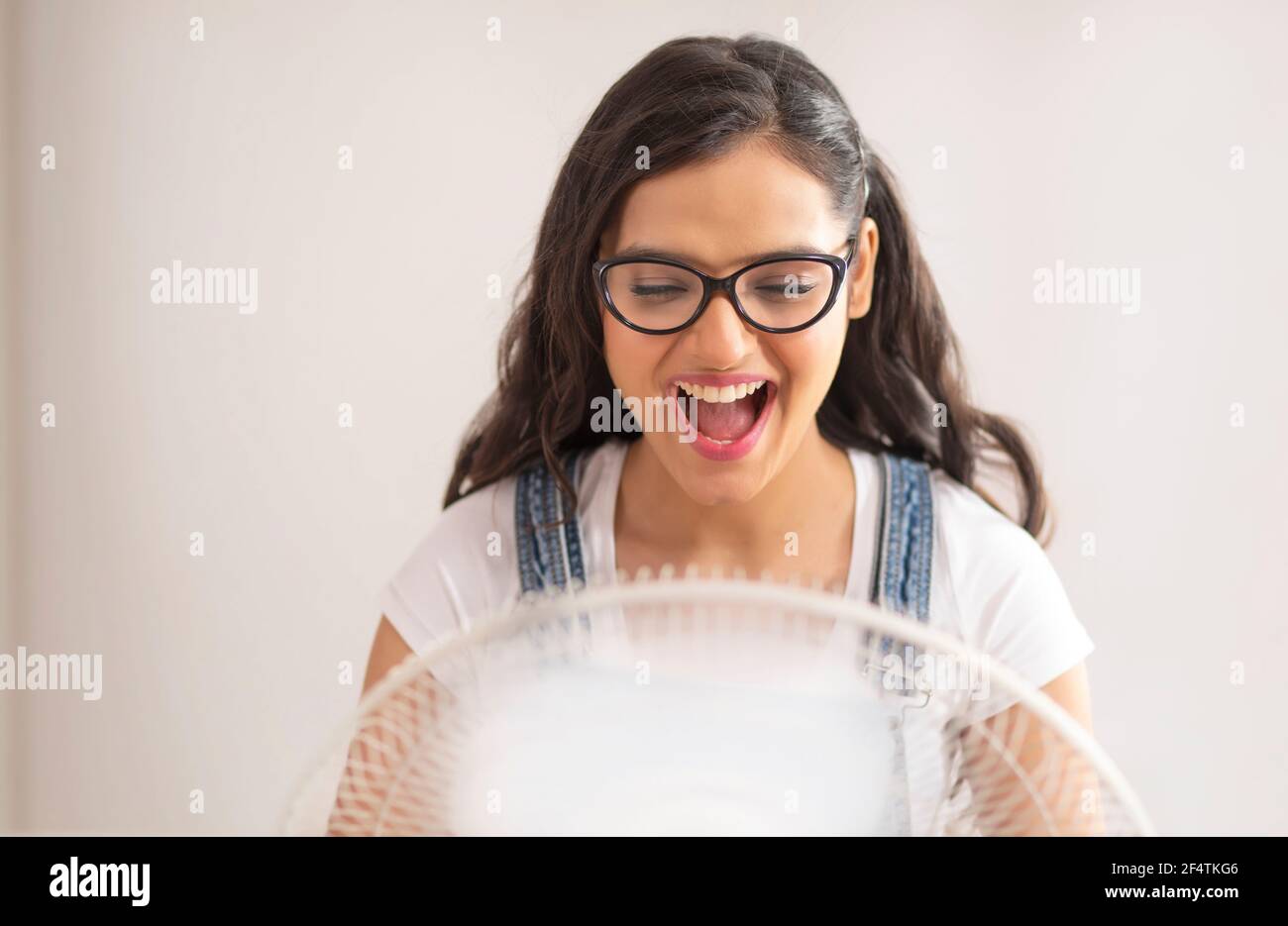 A YOUNG WOMAN HAPPILY STANDING IN FRONT OF A FAN Stock Photo - Alamy