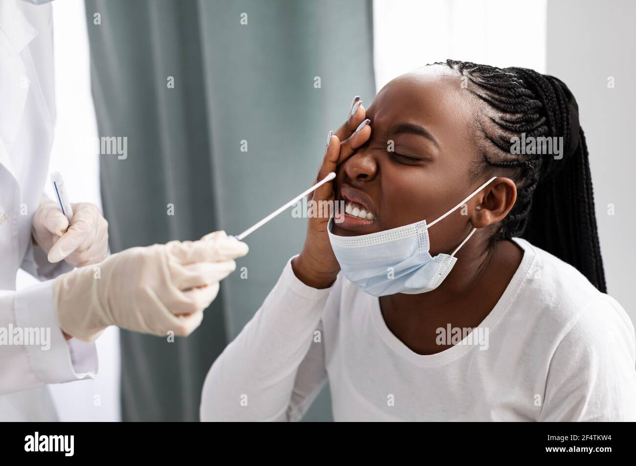 Doctor taking PCR test sample from displeased black woman Stock Photo ...