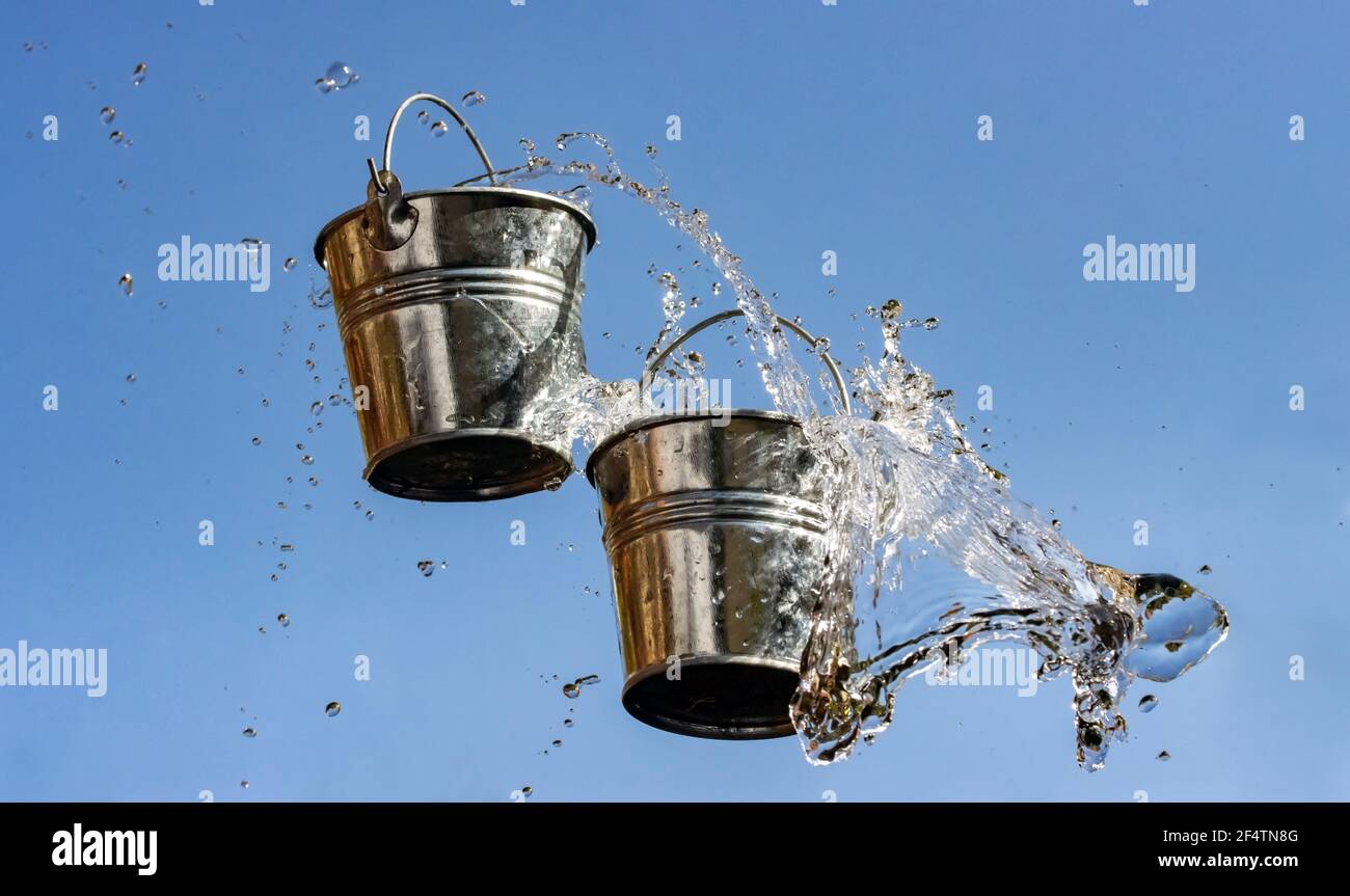 A falling buckets splashes water, on a background of blue sky Stock ...