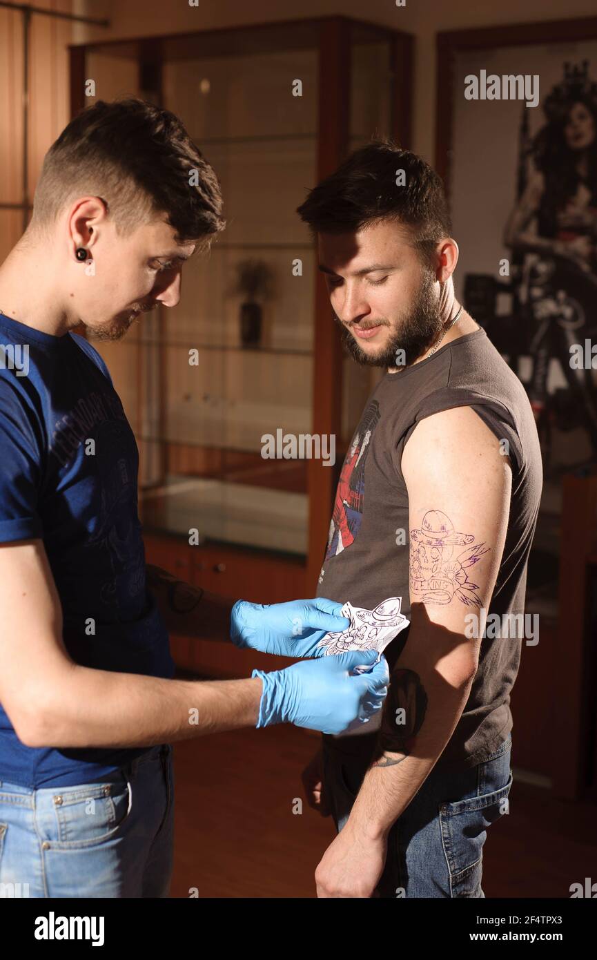 Tattoo artist at work. Man creating picture on hand with it in salon ...