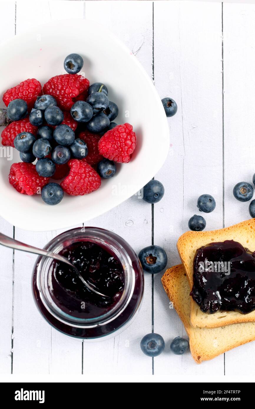 Vertical shot of a bowl of raspberries and blueberries on the table ...
