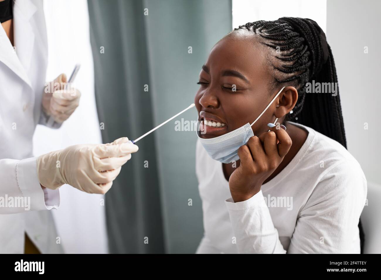 Doctor taking PCR test sample from displeased afro woman Stock Photo ...
