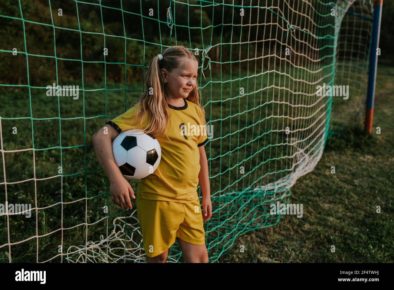 Girl goalkeeper standing at goal on soccer field. Girl in yellow ...
