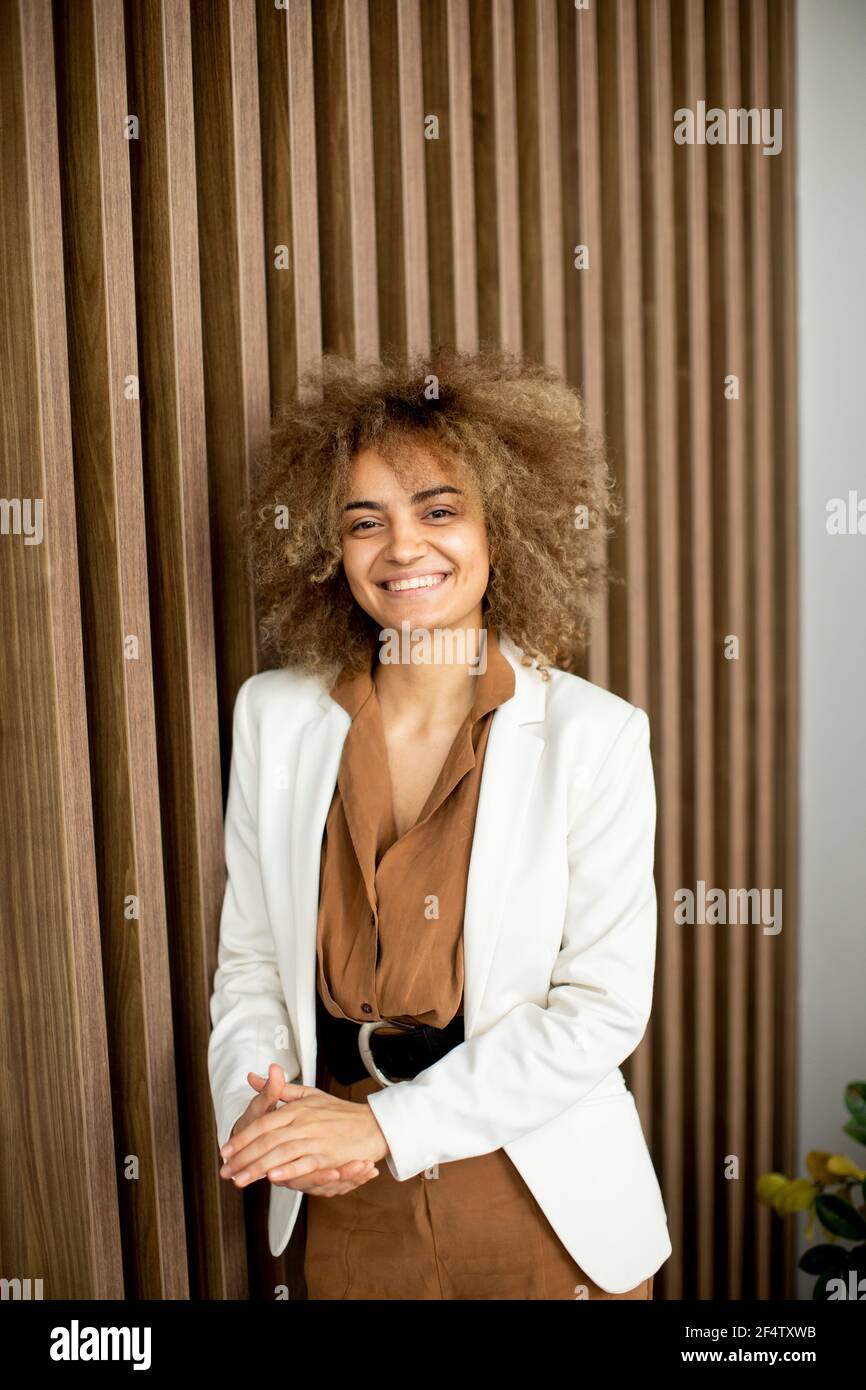 Pretty young curly hair woman standing in modern office Stock Photo - Alamy