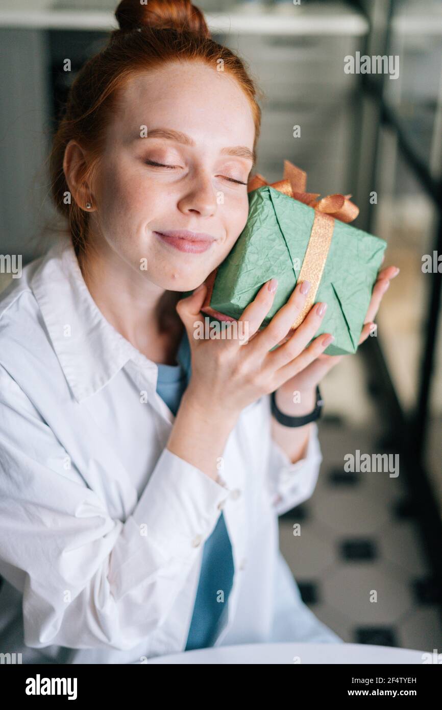 Close-up face of cheerful redhead young woman gently cradling surprise ...