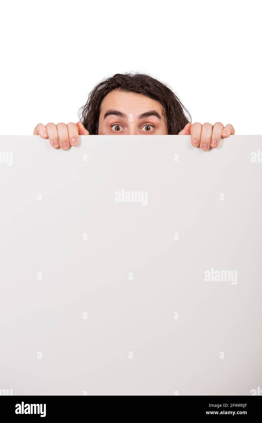 Fearful man lurking behind a blank whiteboard. Empty sheet with copy ...