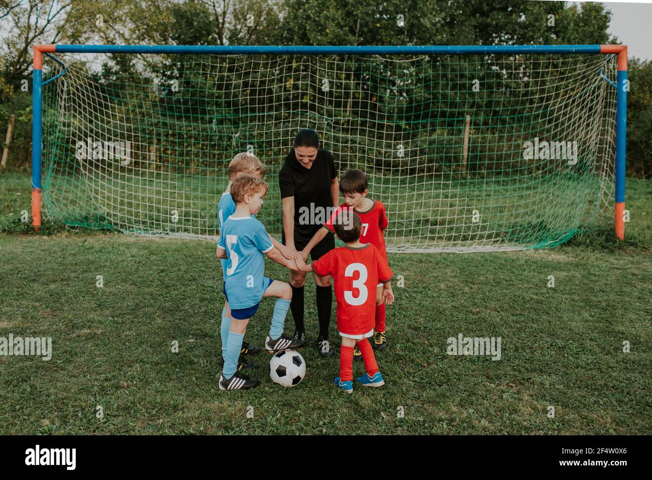 Children in football dresses putting hands together at beginning of ...
