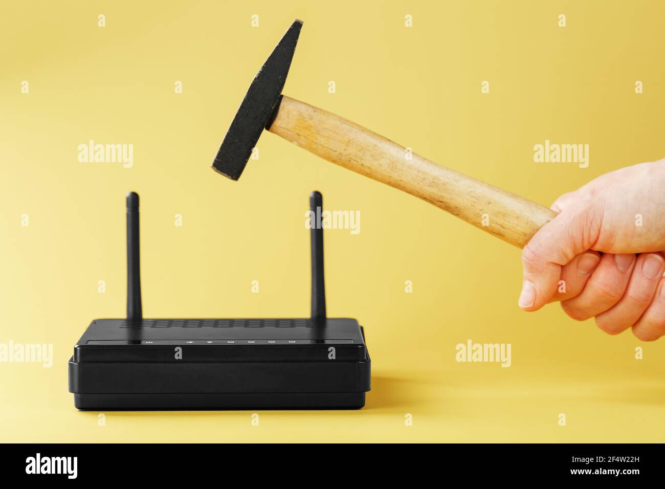 Hammer over the Wi-Fi router for destruction on a yellow background ...