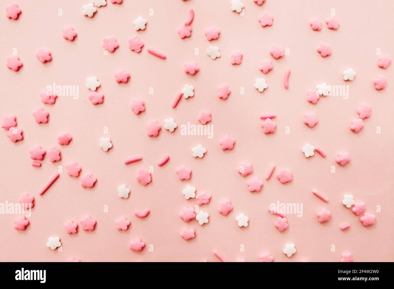 Pink and white star shaped sprinkles on light pink background ...