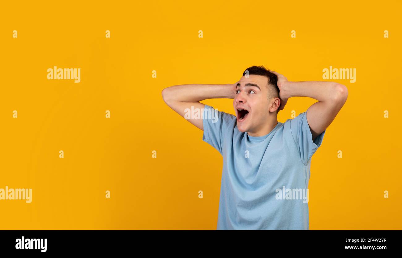 Cool young guy holding his head in shock, screaming OMG and looking ...