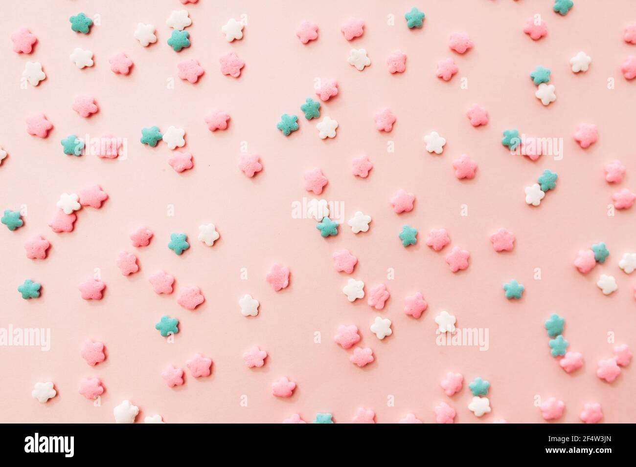 Pink, white and blue star shaped sprinkles on light pink background ...