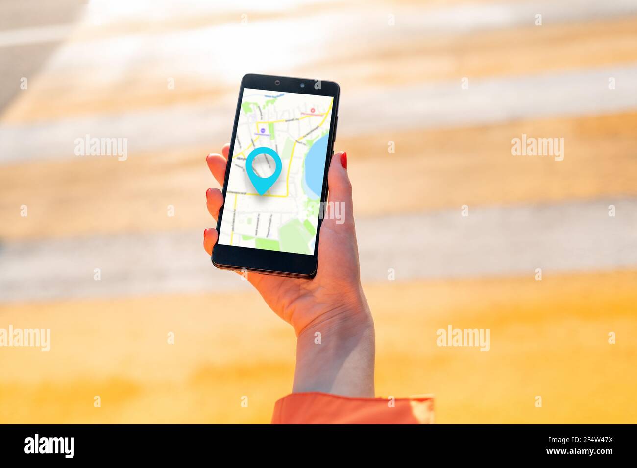 A woman's hand holds a smartphone with an online map that has a blue ...