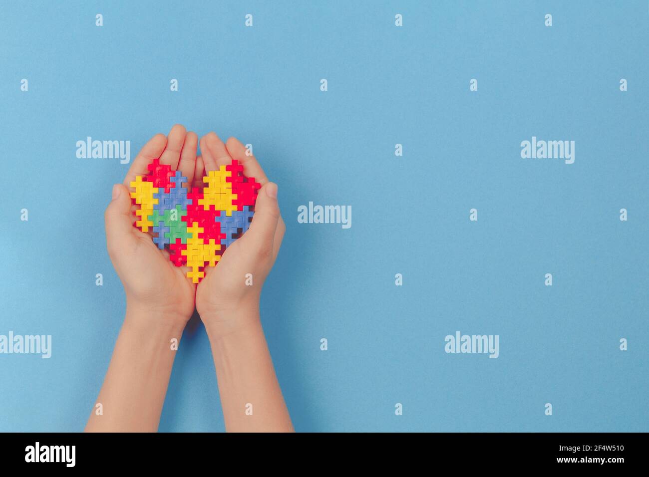 Kid hand holding colorful heart on light blue background. World autism ...