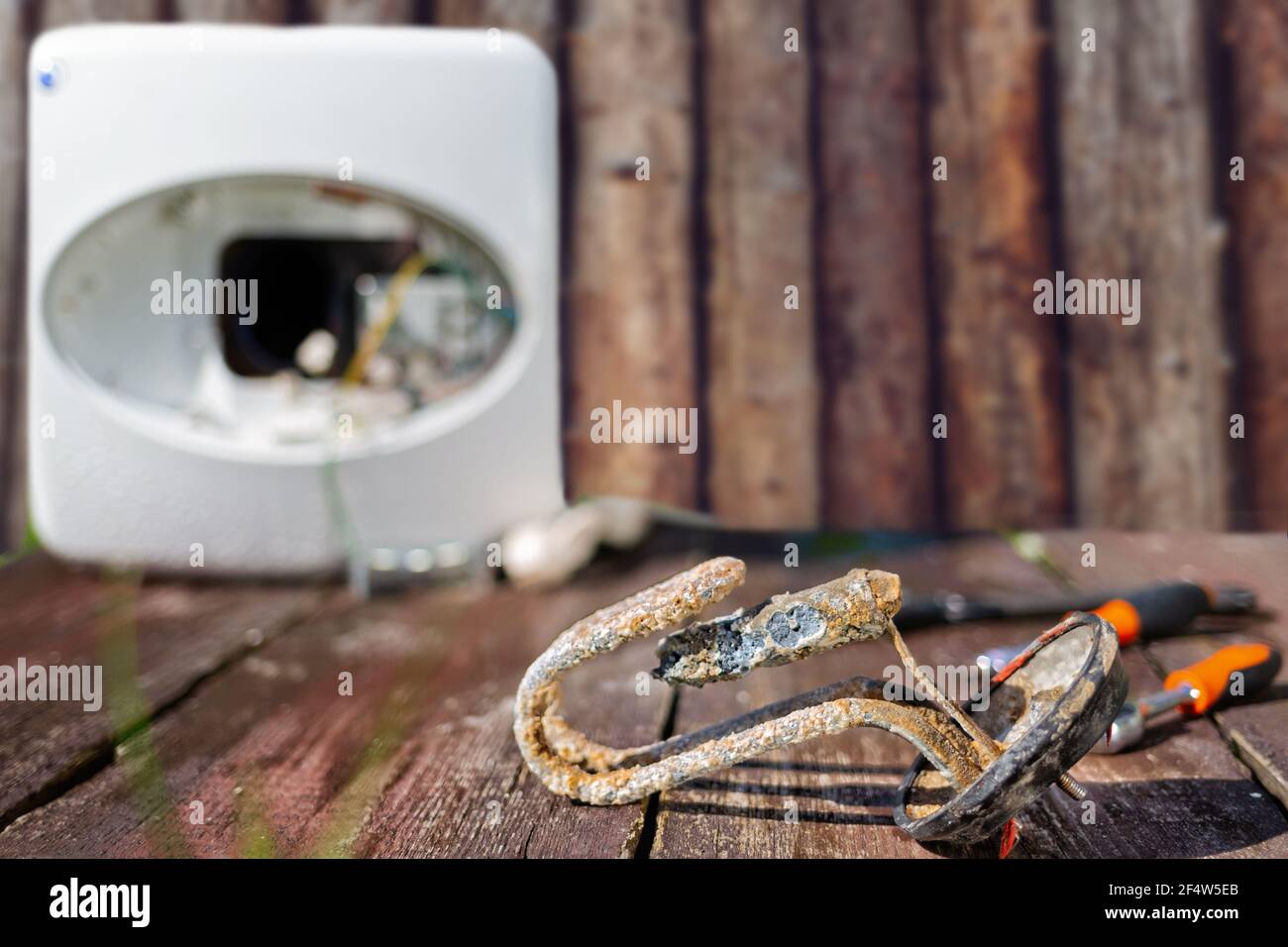 Heating element, rust and scale on boiler background, lying on wooden ...