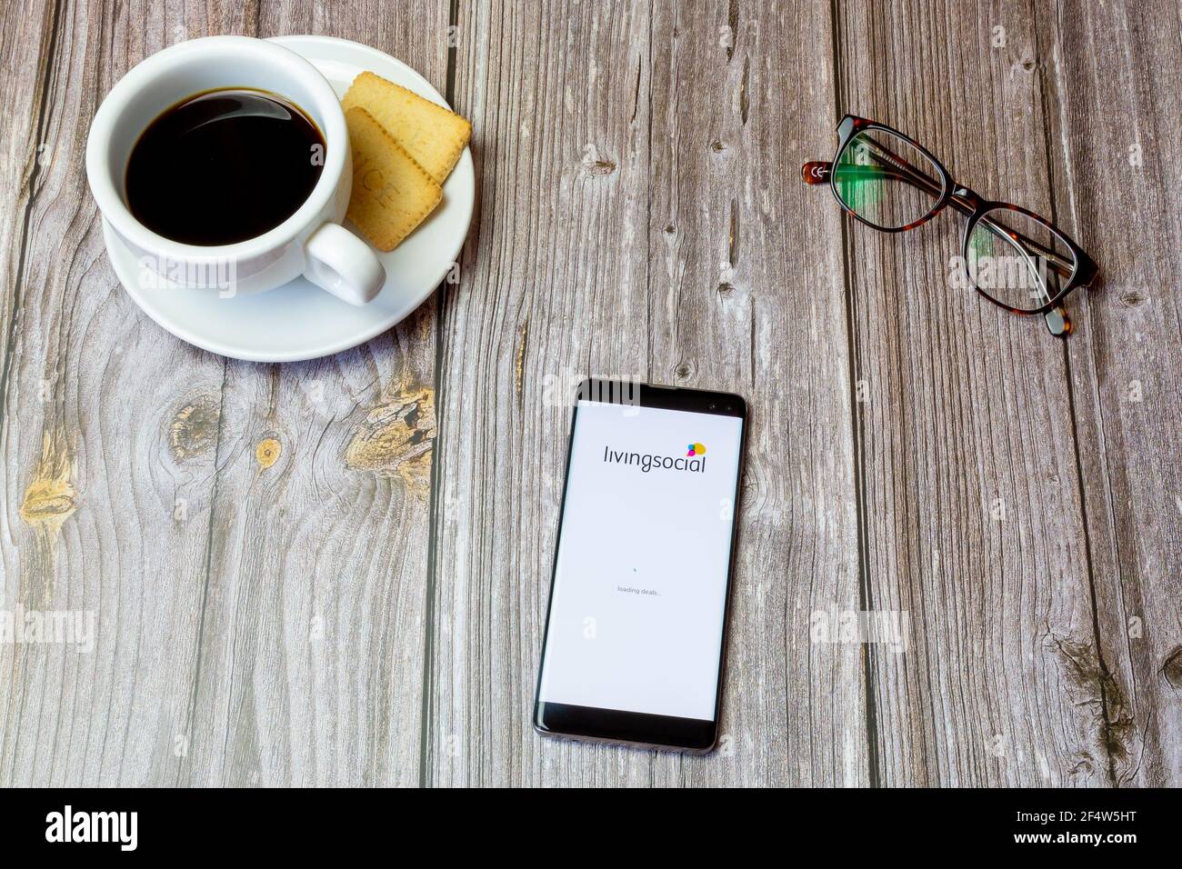 A mobile phone or cell phone laid on a wooden table with the ...