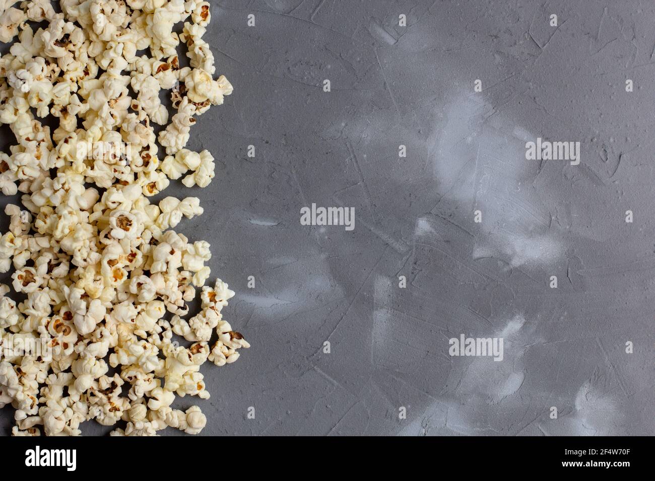 Border of fresh popcorn on grey stone background. Top view with copy ...