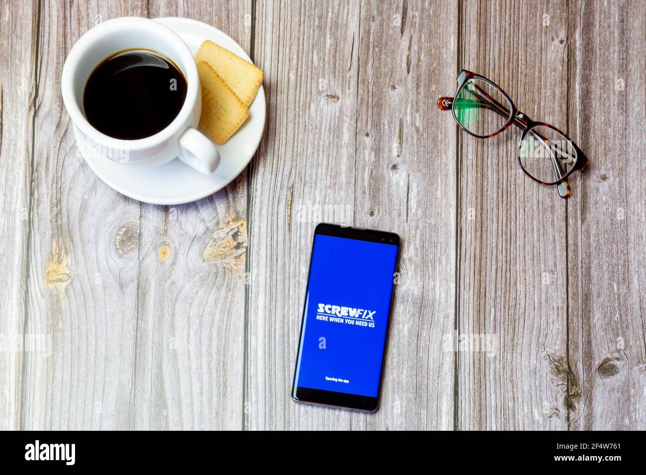 A mobile phone or cell phone laid on a wooden table with the Screwfix ...