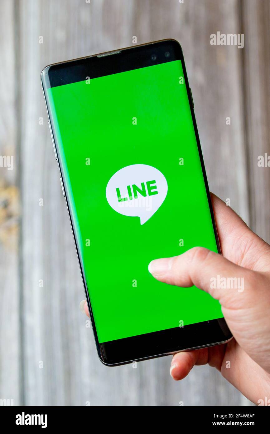 A mobile phone or cell phone being held in a hand with the Line app ...