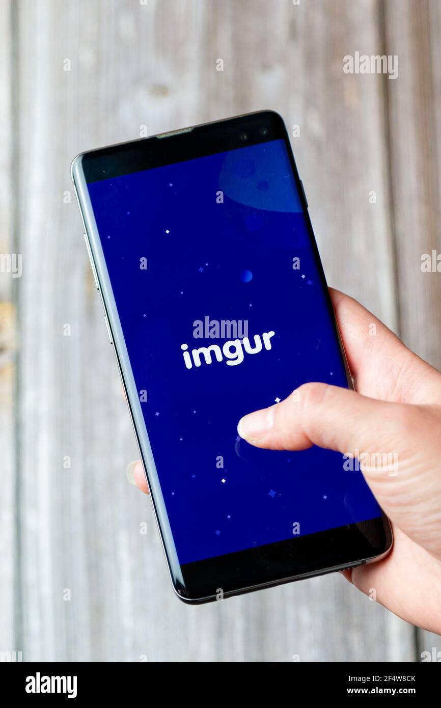 A mobile phone or cell phone being held in a hand with the Imgur app ...