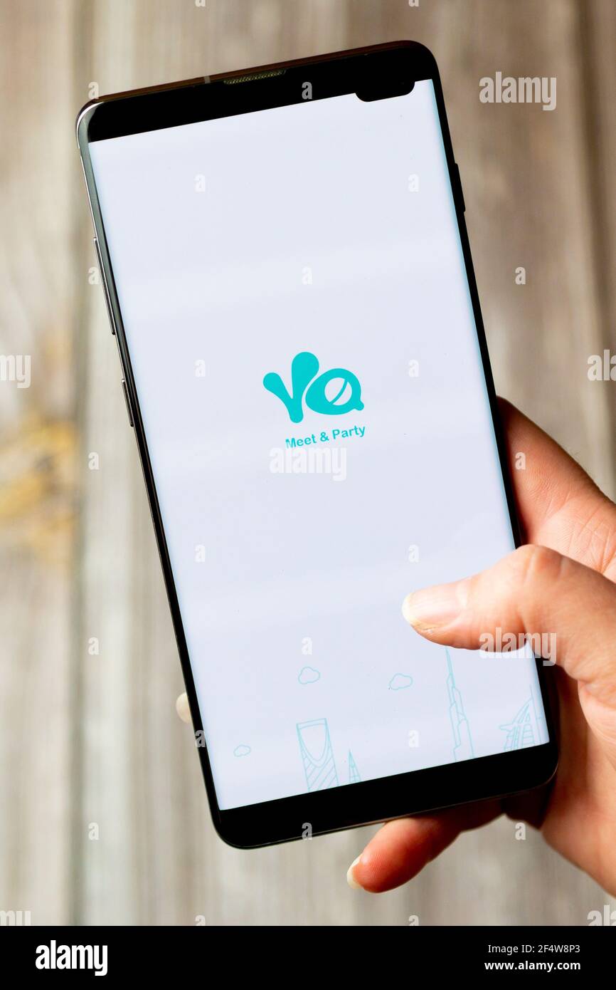 A mobile phone or cell phone being held in a hand with the Yalla app ...