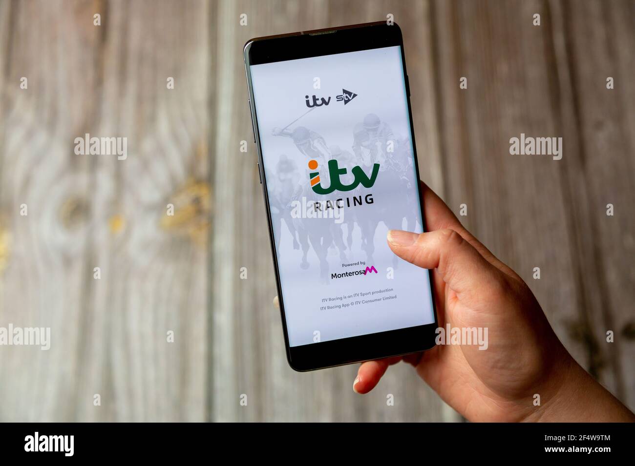 A mobile phone or cell phone being held in a hand with the ITV Racing ...