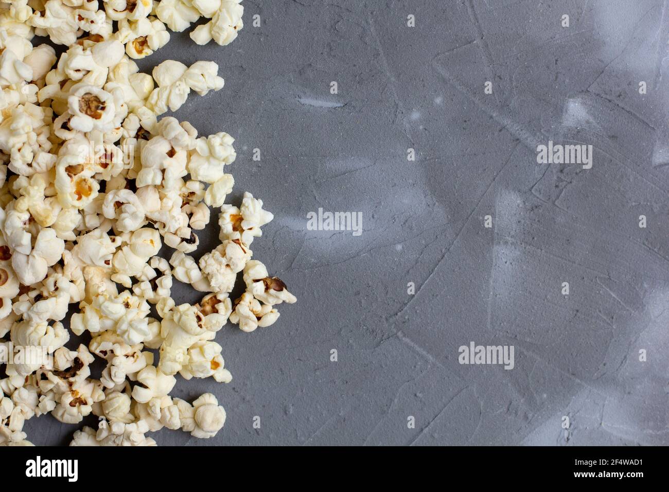 Border of fresh popcorn on grey stone background. Top view with copy ...