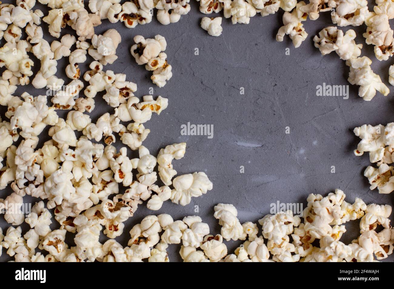 Frame of fresh popcorn on grey stone background. Top view with copy ...
