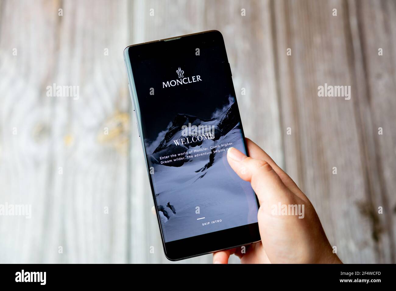 A mobile phone or cell phone being held in a hand with the Moncler app ...
