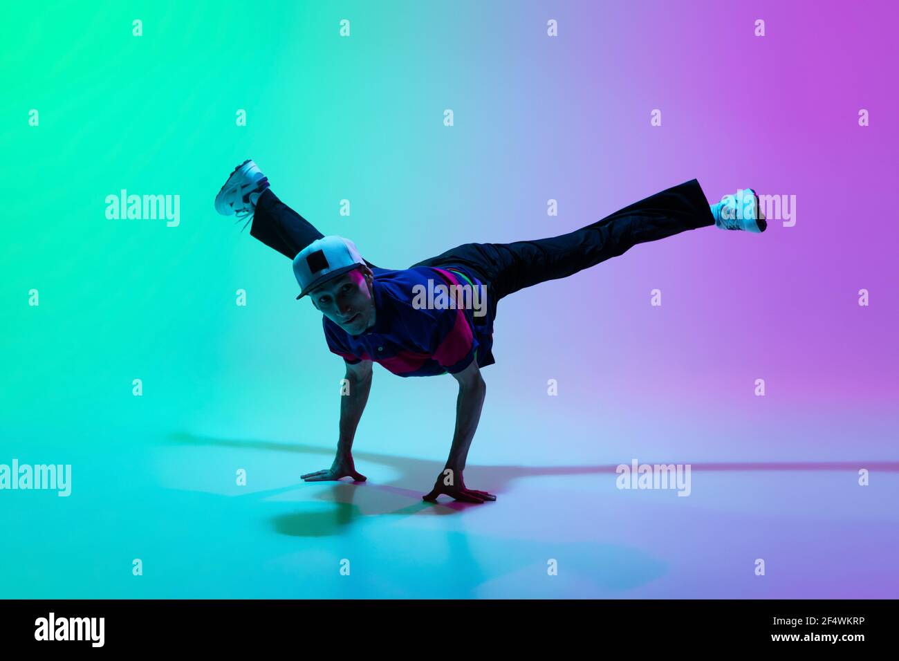 Beautiful sportive boy dancing hip-hop in stylish clothes on colorful ...