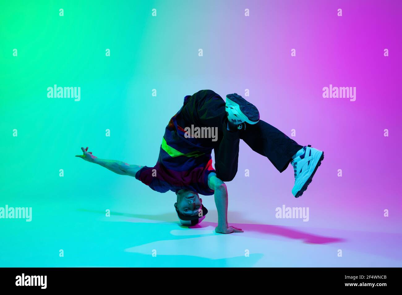 Beautiful sportive boy dancing hip-hop in stylish clothes on colorful ...