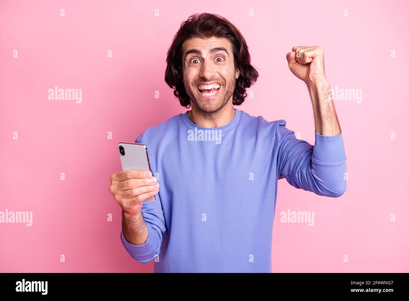 Portrait of hooray guy hold telephone hand fist wear purple sweater ...