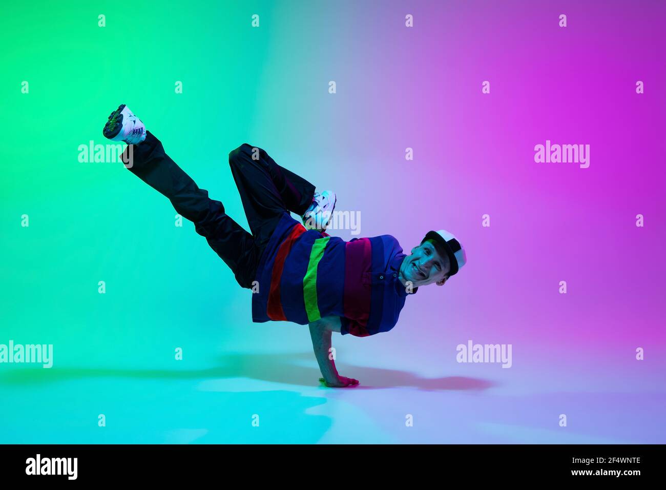 Beautiful sportive boy dancing hip-hop in stylish clothes on colorful ...