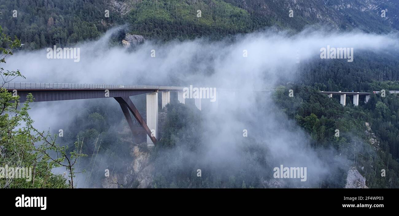 the Cadore bridge located in the Dolomites with the fog that clears as ...