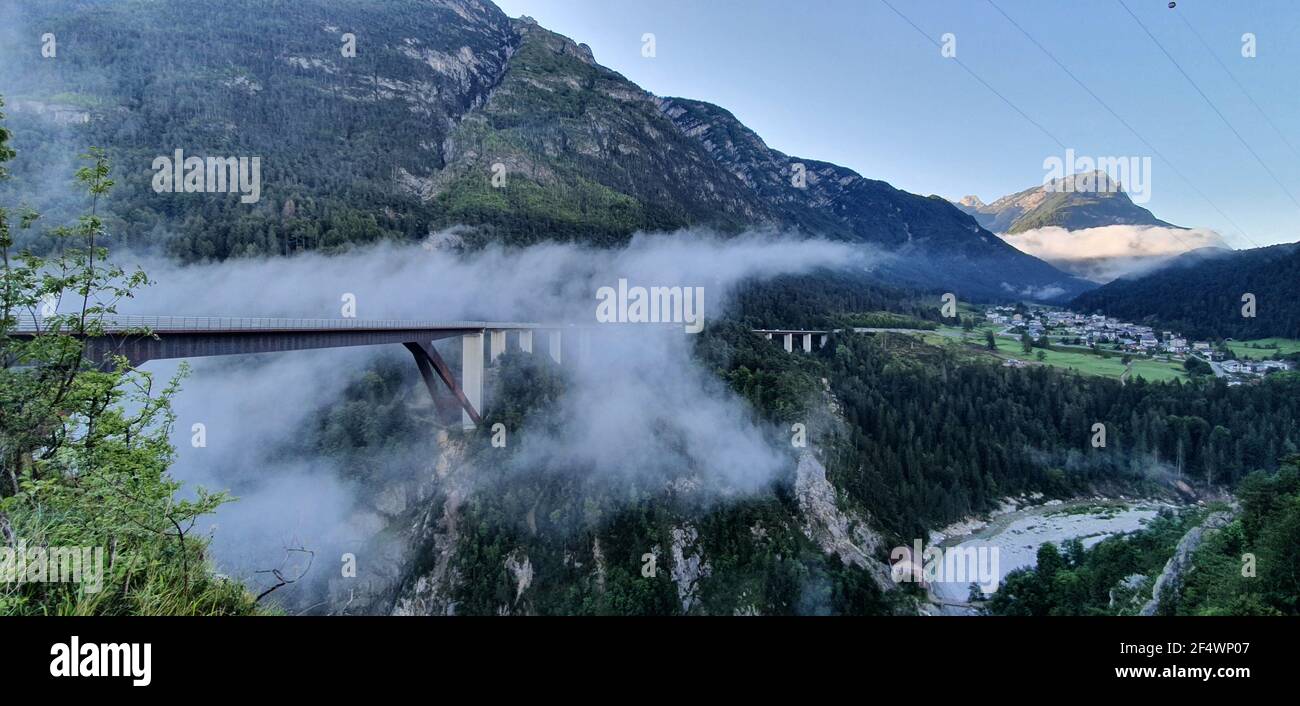 the Cadore bridge located in the Dolomites with the fog that clears as ...