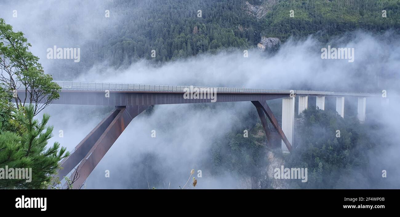 the Cadore bridge located in the Dolomites with the fog that clears as ...