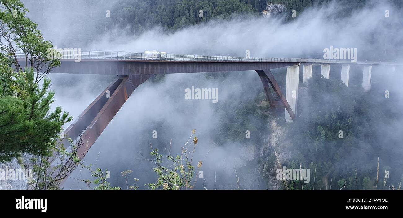 the Cadore bridge located in the Dolomites with the fog that clears as ...