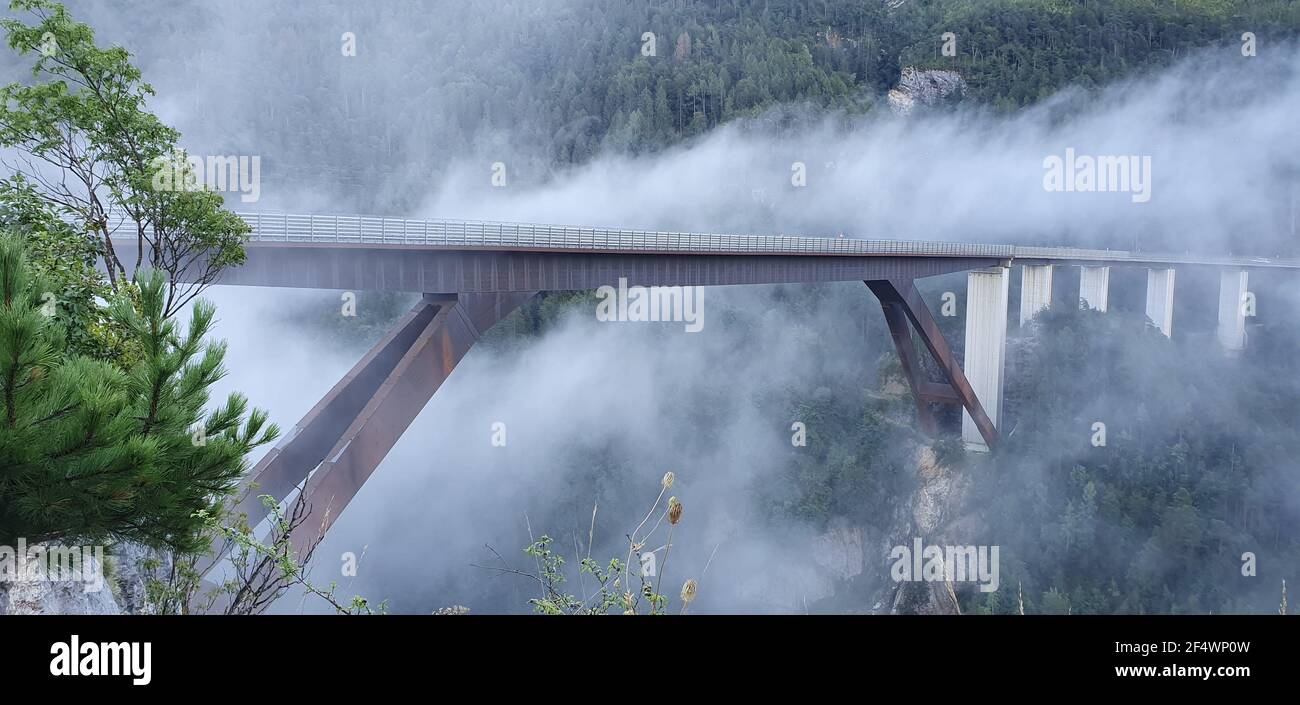 the Cadore bridge located in the Dolomites with the fog that clears as ...