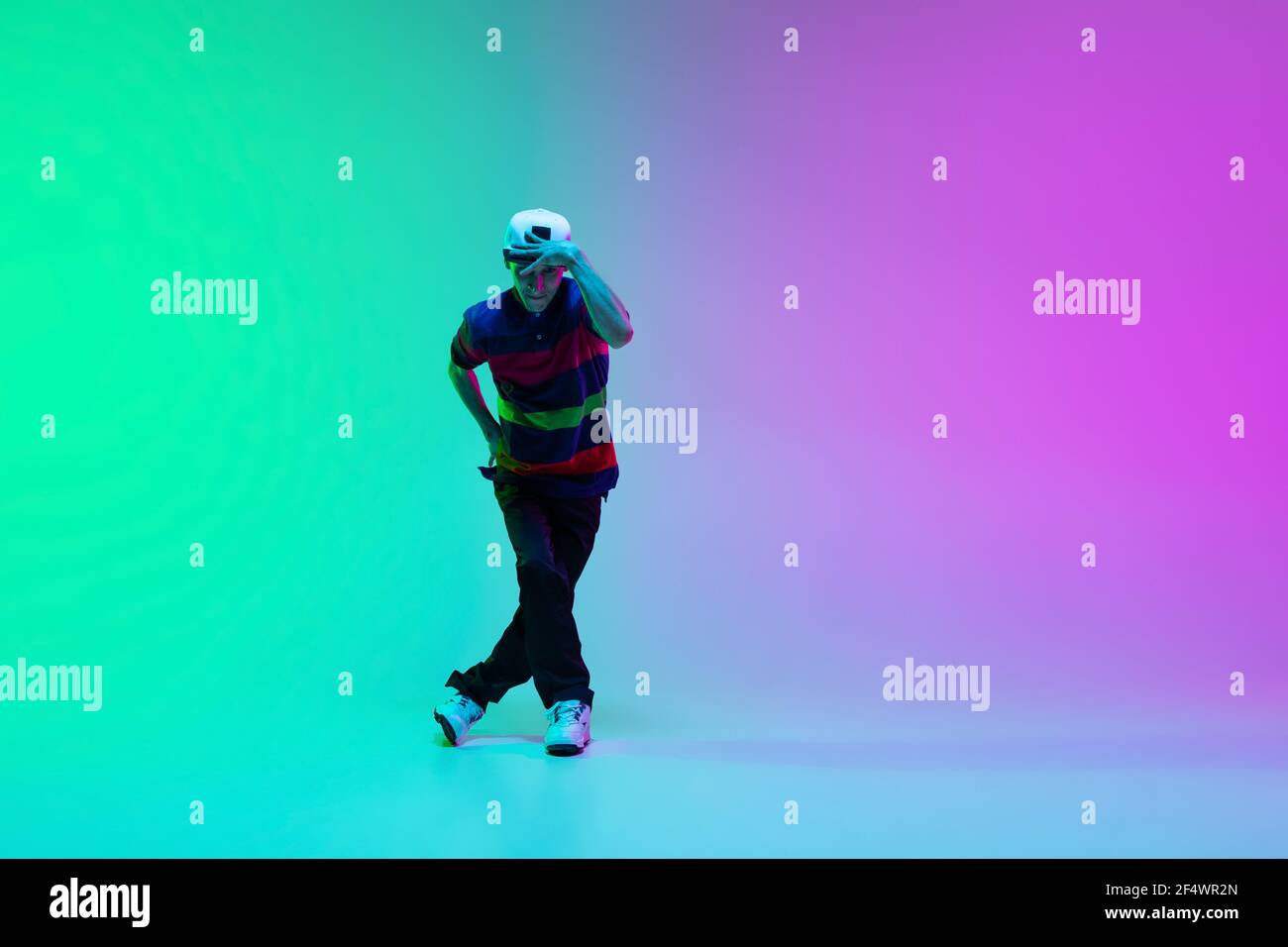 Beautiful sportive boy dancing hip-hop in stylish clothes on colorful ...