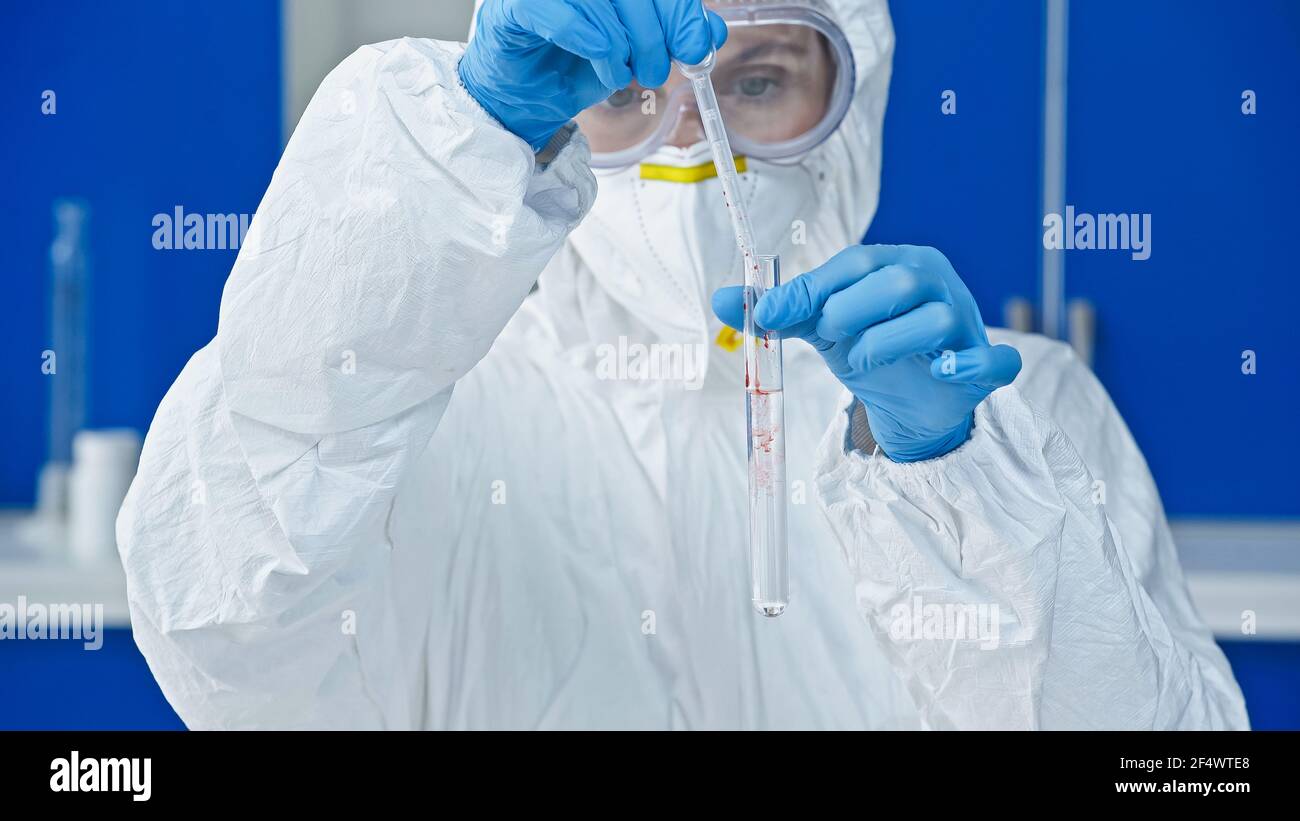 virologist in hazmat suit holding test tube and dropper in laboratory ...