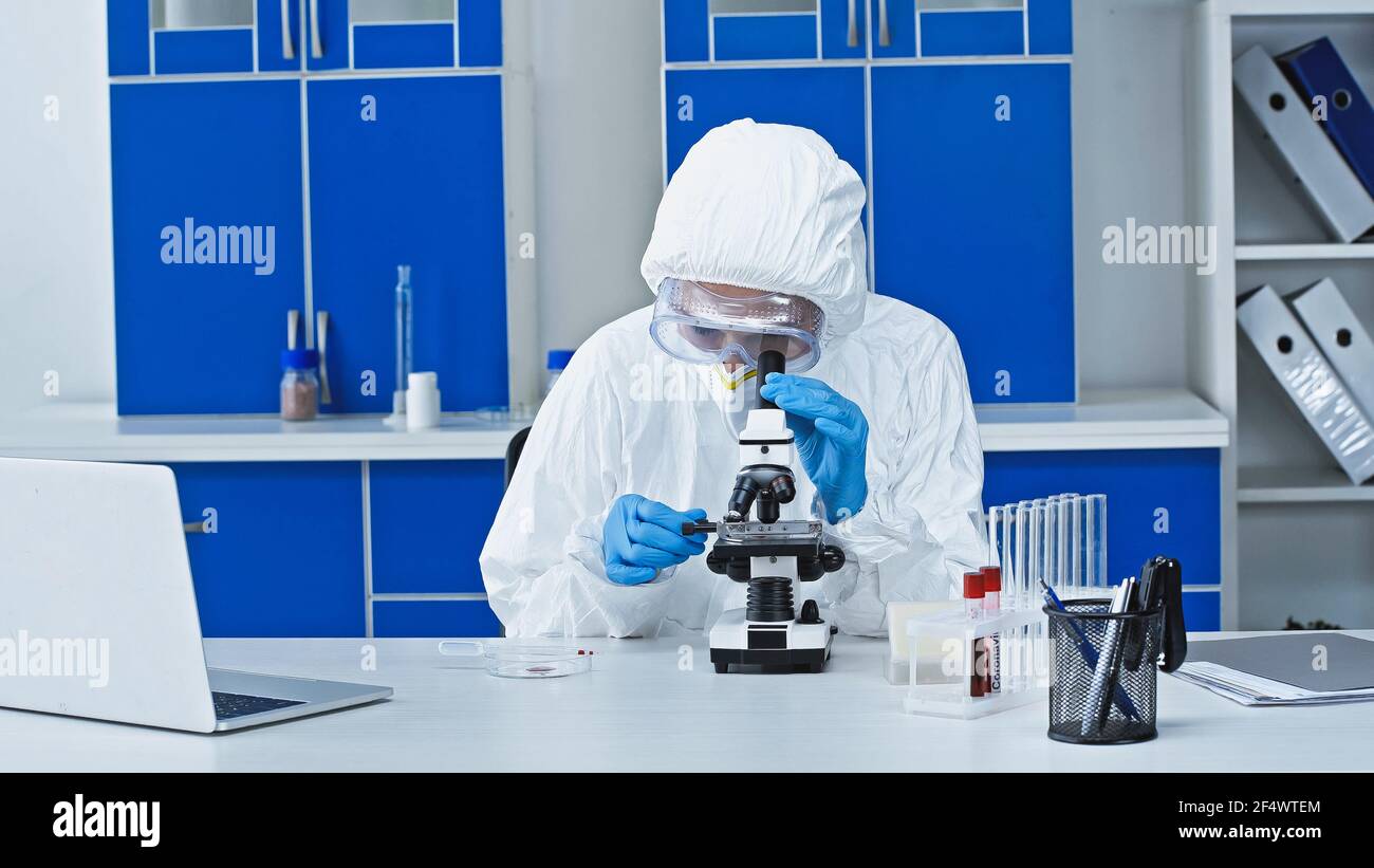 scientist in hazmat suit working with microscope in laboratory Stock ...