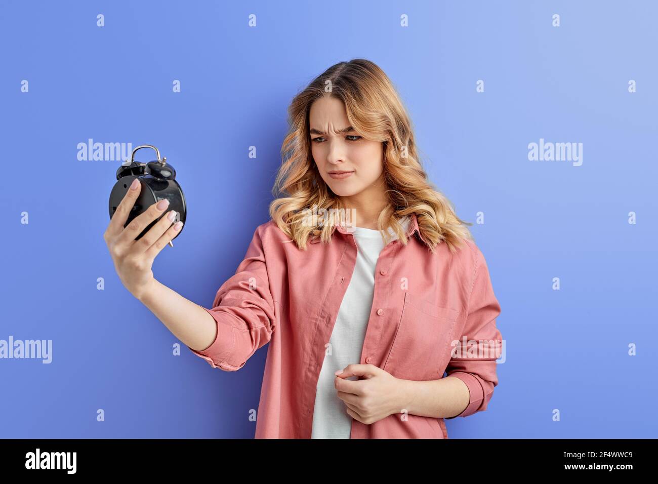 confused female teen look at clocks with dissapointment, need more time ...