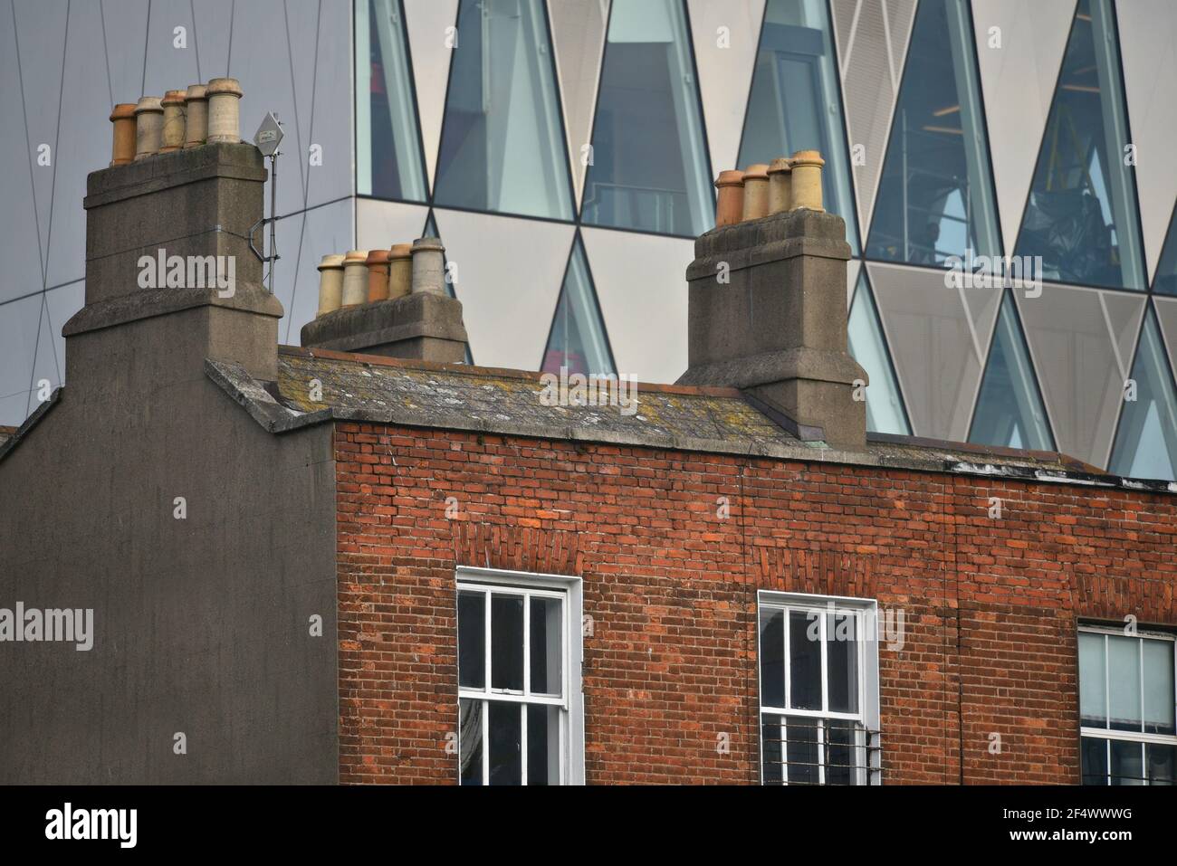 Old brick building against a modern glass facade corporate building in ...