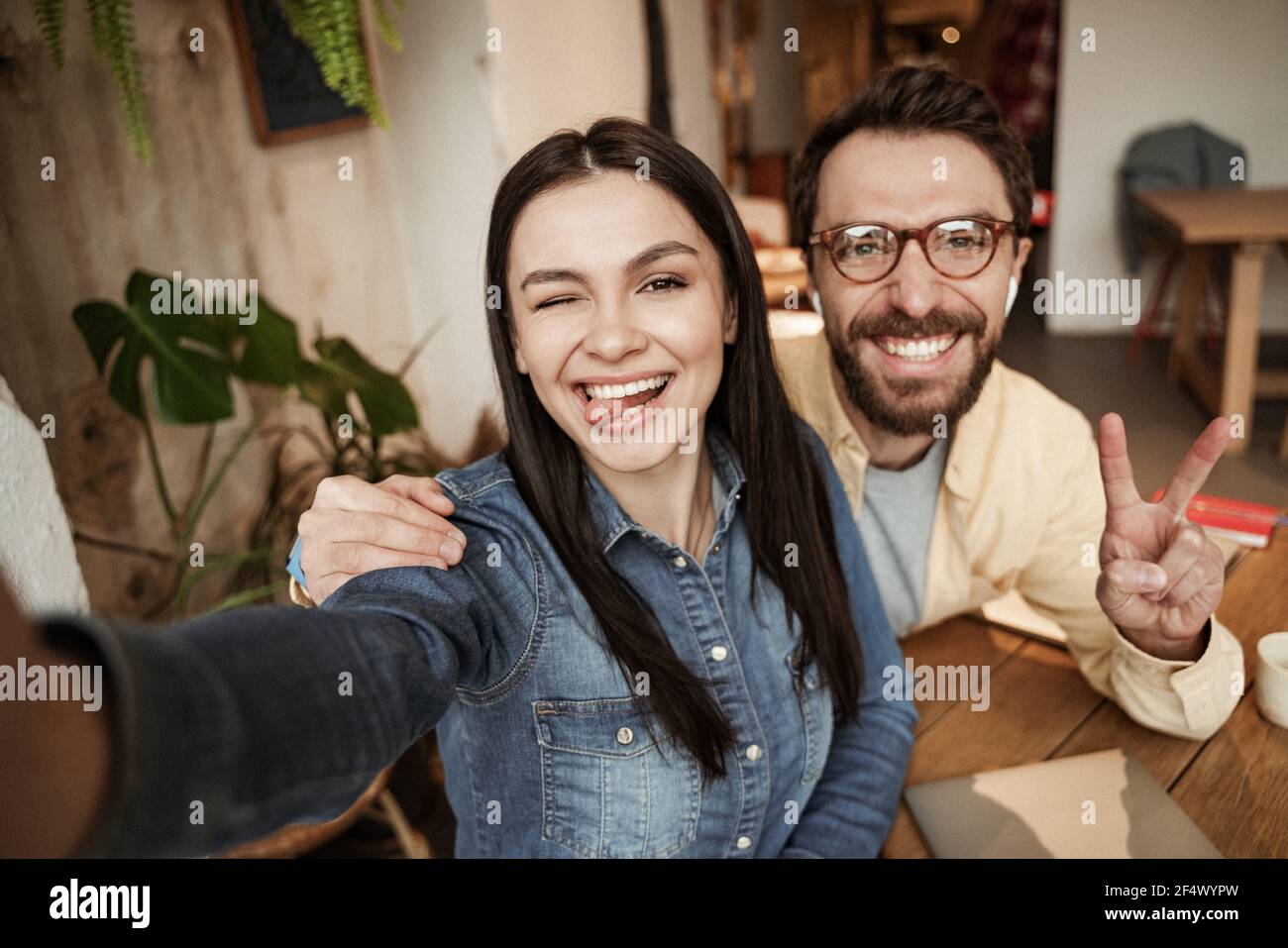 cheerful woman sticking out tongue near man showing peace sign Stock ...