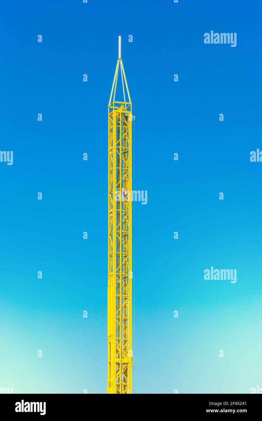 Attraction yellow tower in an amusement park against a blue sky ...