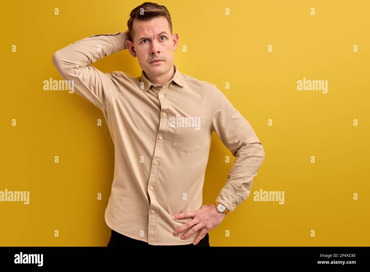doubtful young man stand thinking, scratch back of head thinking about ...