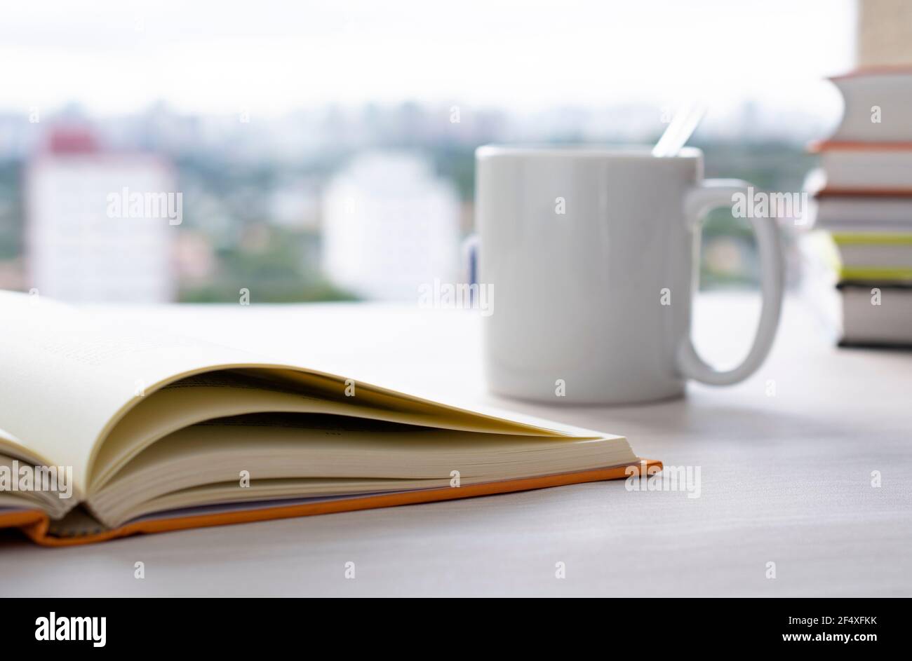 Open book, coffee cup and pile of books over wood table with cityscape ...