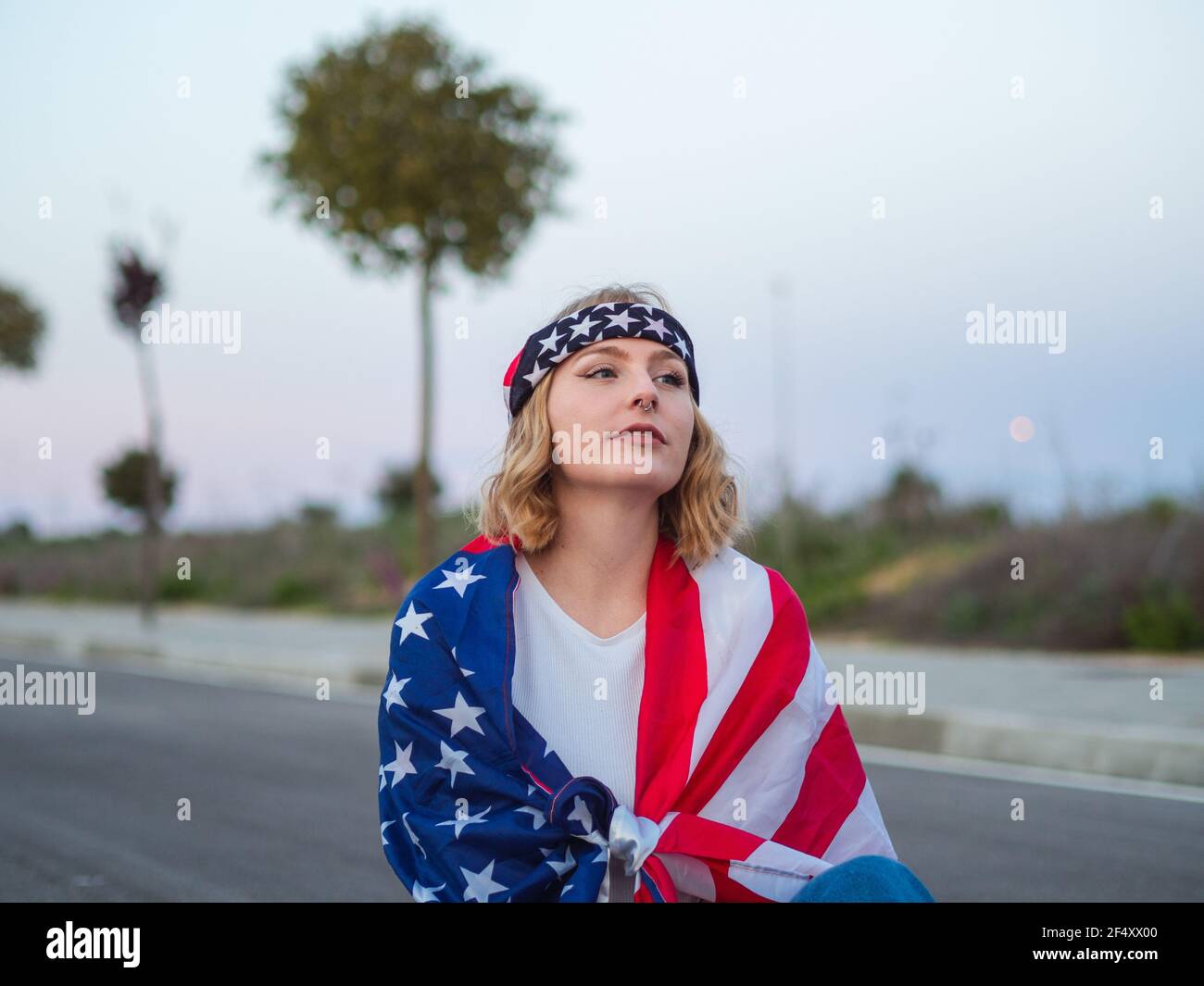 Patriotic Caucasian sitting in the middle of the road with the US flag ...