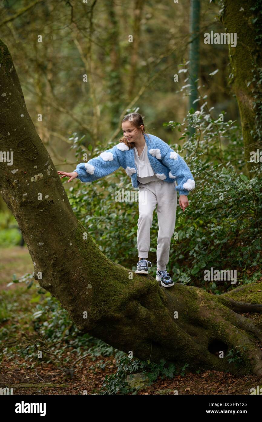 Young Girl crouching on a Tree Trunk Stock Photo - Alamy